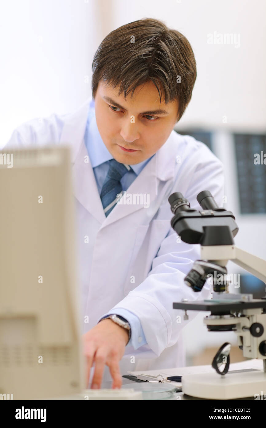 Researcher working in medical laboratory using microscope and computer ...