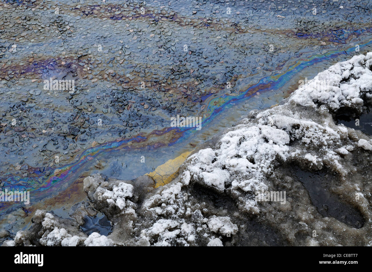 An oil streak running down the side of a road lined with snowy slush ...