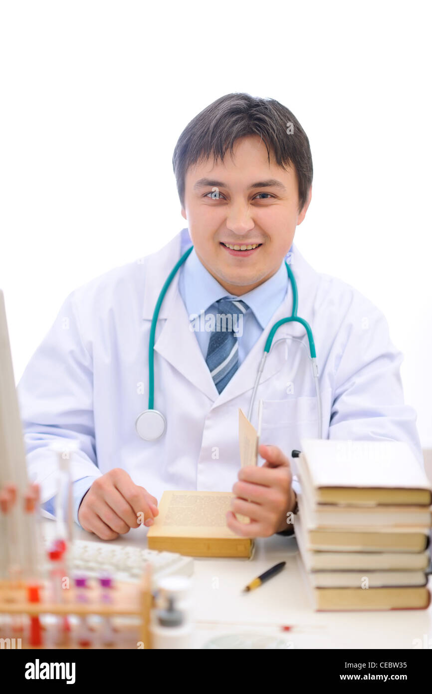 Smiling medical doctor sitting at table and reading book Stock Photo ...