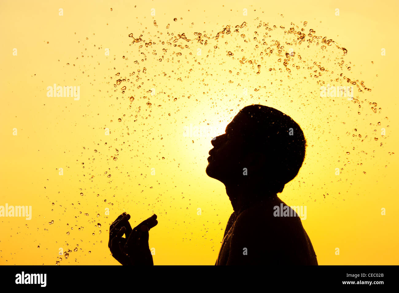 Indian man splashing water over himself at sunset. Silhouette. India ...