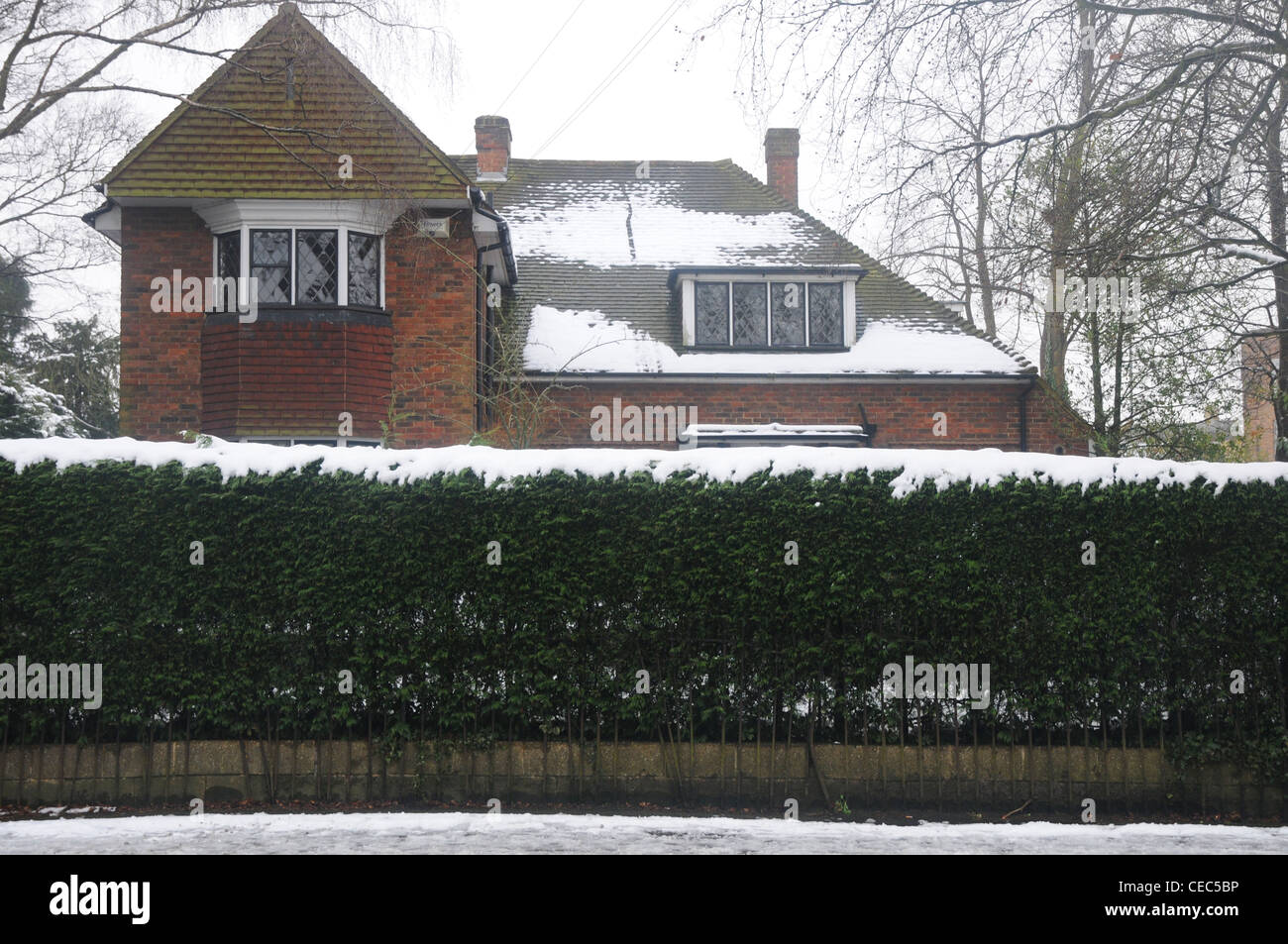 Large brick house, snow on roof, snow on green hedge, winter Stock ...