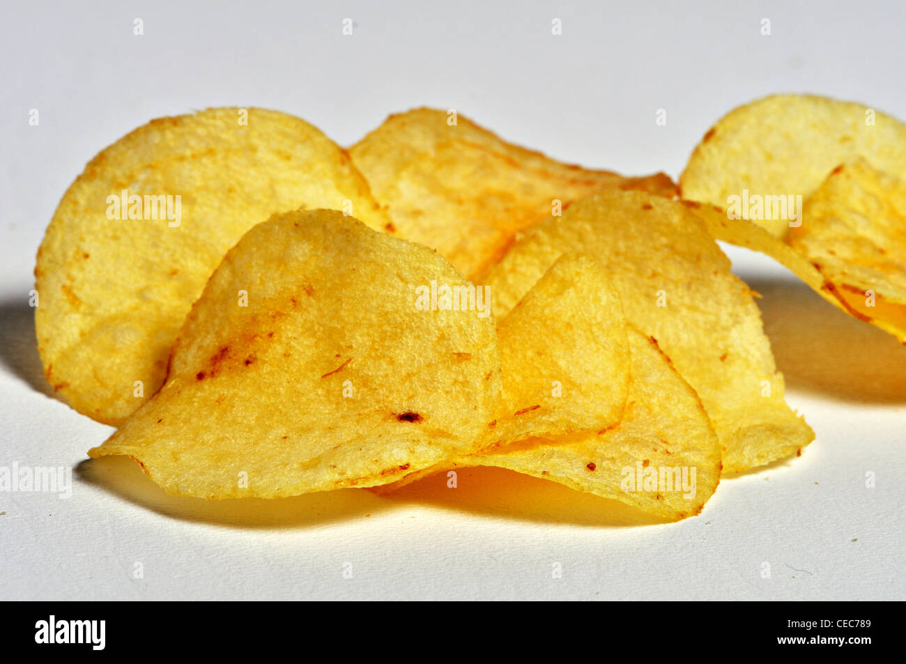 A small pile of crunchy potato chips lay on a plain background Stock ...