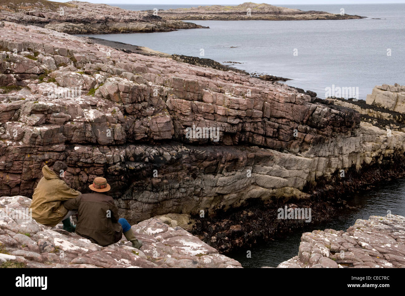 Rear view of ramblers sitting on the cliffs, Wester Ross, Scotland, UK ...