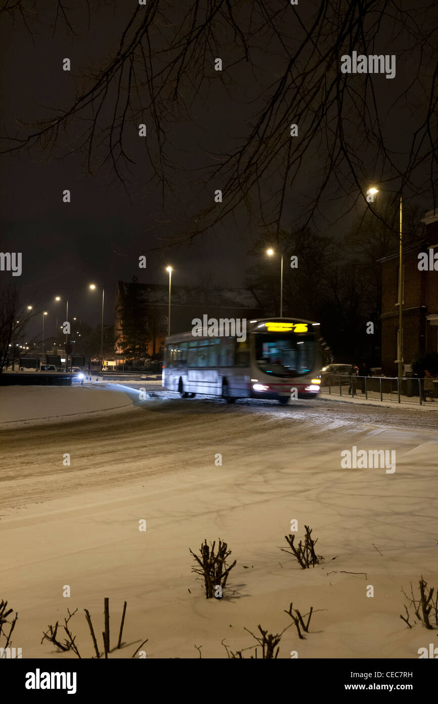 Bus with lights driving around a roundabout in wintery/snowy weather at ...