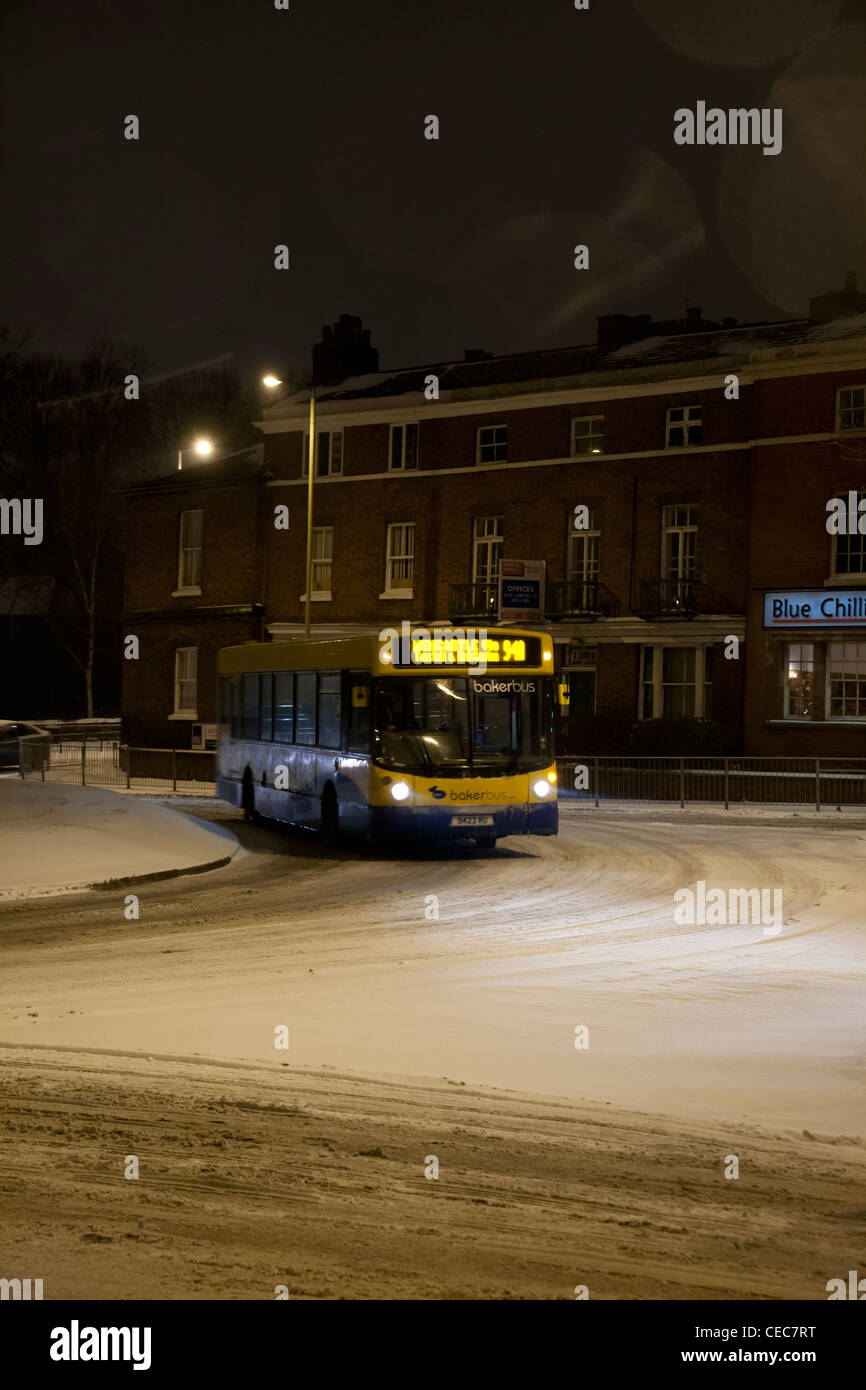 Bus with lights driving around a roundabout in wintry/snowy weather at ...