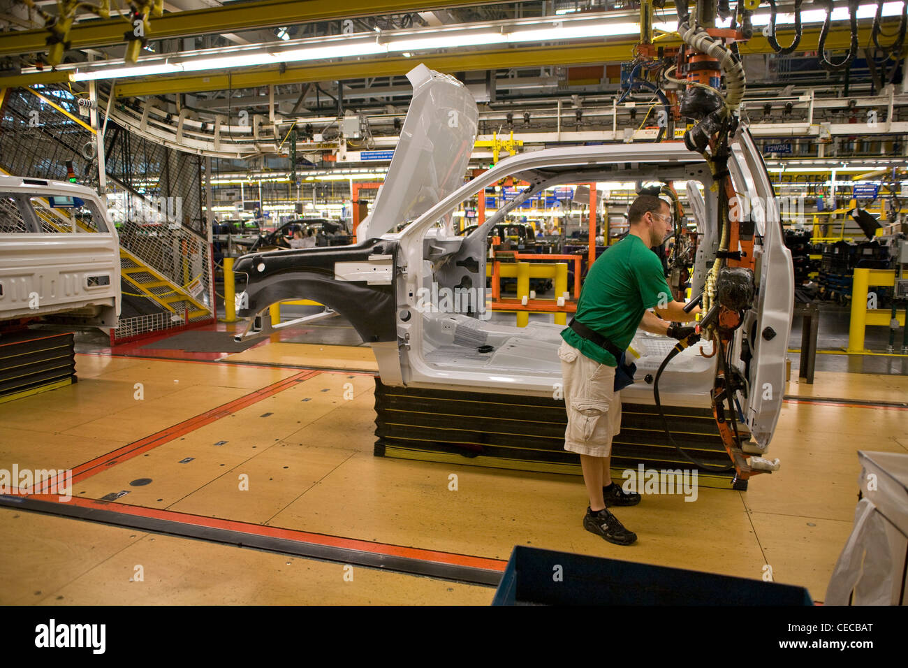 A factory worker installs door hardware on an F-150 pickup truck at the ...