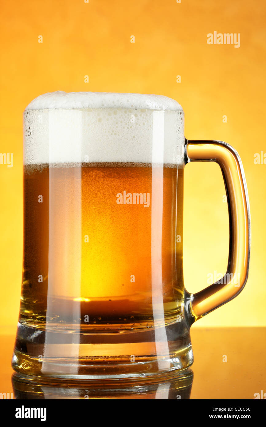 Beer mug with froth over yellow background Stock Photo - Alamy