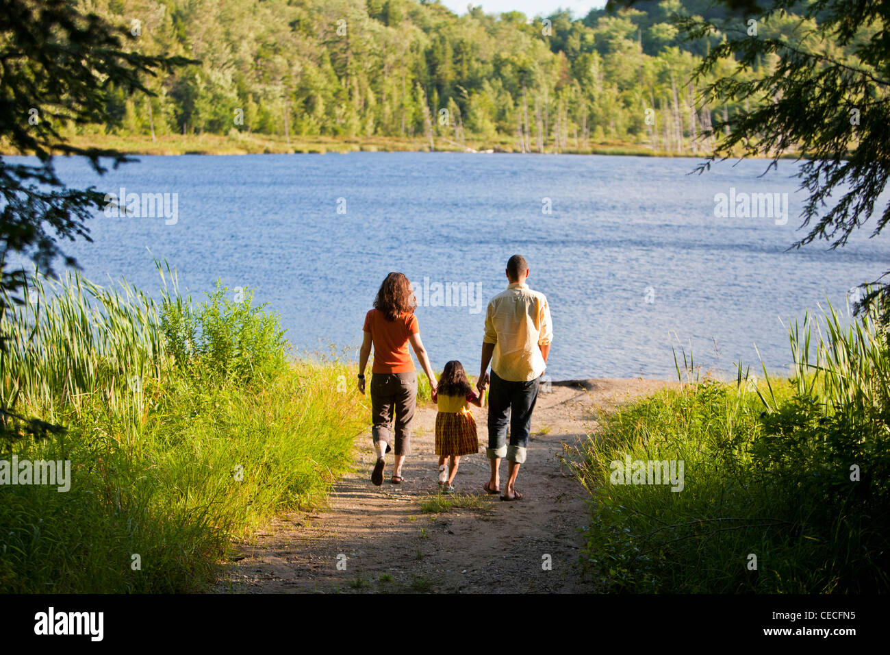 A woman, man, and young girl walk on a path to Mud Pond in Zack Woods ...