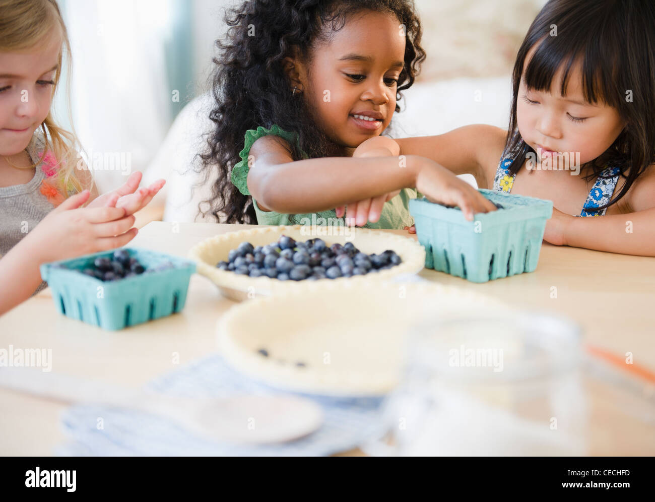 Girls putting blueberries into bowl together Stock Photo - Alamy