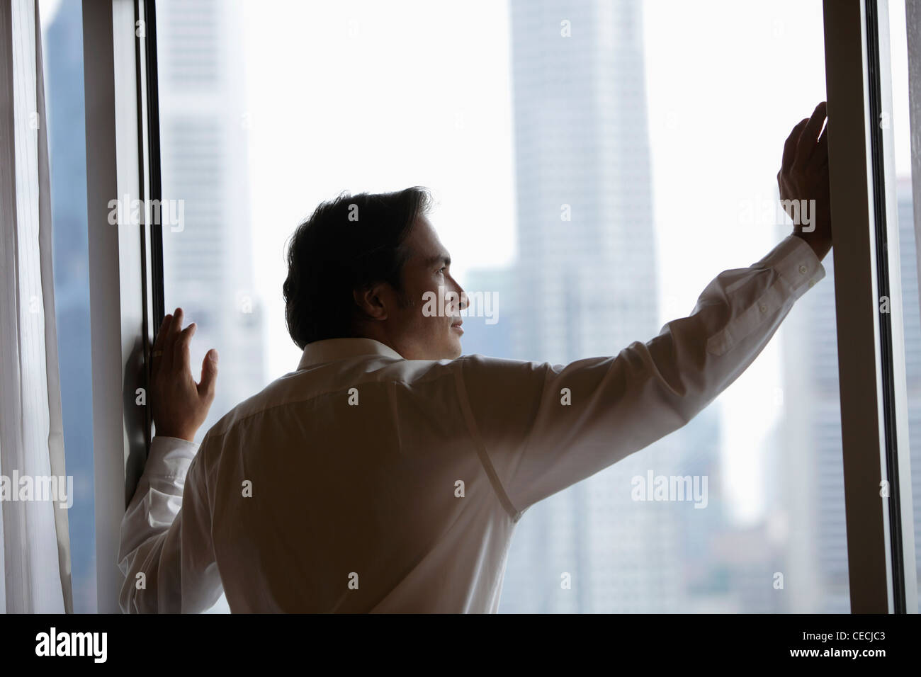 Profile of man looking out of window at city Stock Photo - Alamy