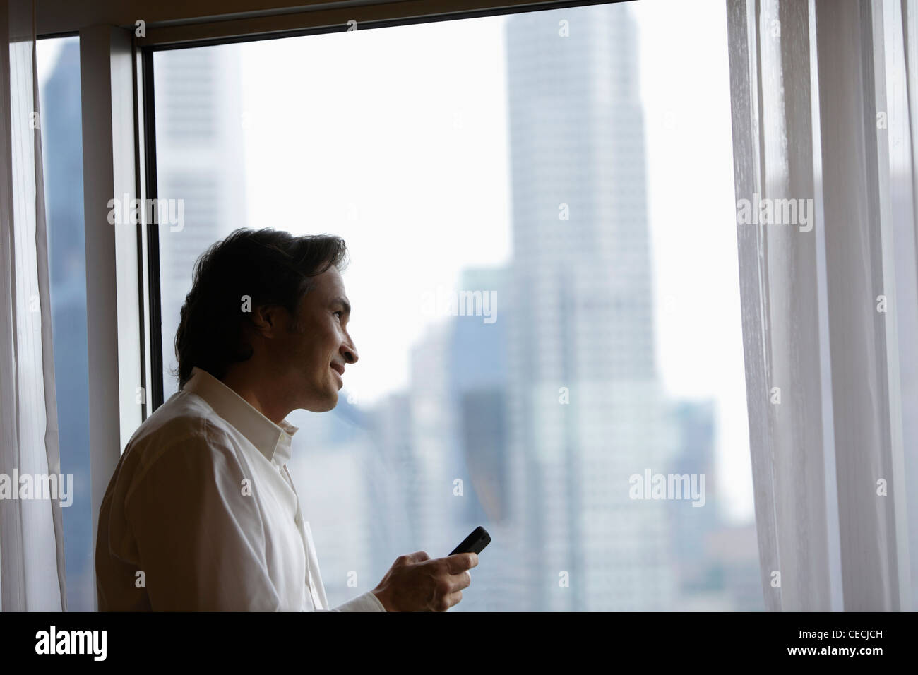 Man looking out of window smiling Stock Photo - Alamy