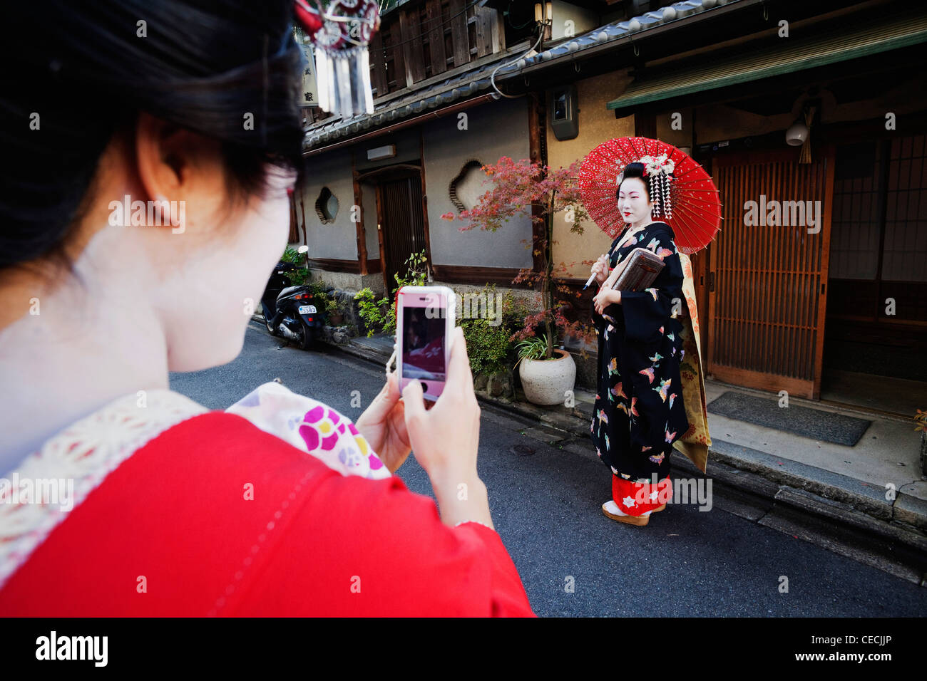 Woman taking photo of Geisha dressed up in traditional Japanese clothes ...