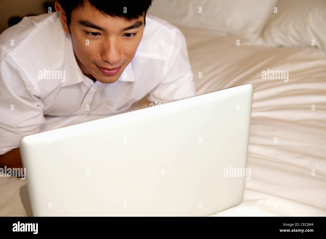 man laying on bed working on laptop Stock Photo - Alamy