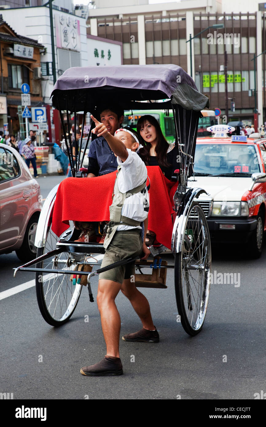 Couple taking a rickshaw ride on busy street in Tokyo Asakusa, Japan ...