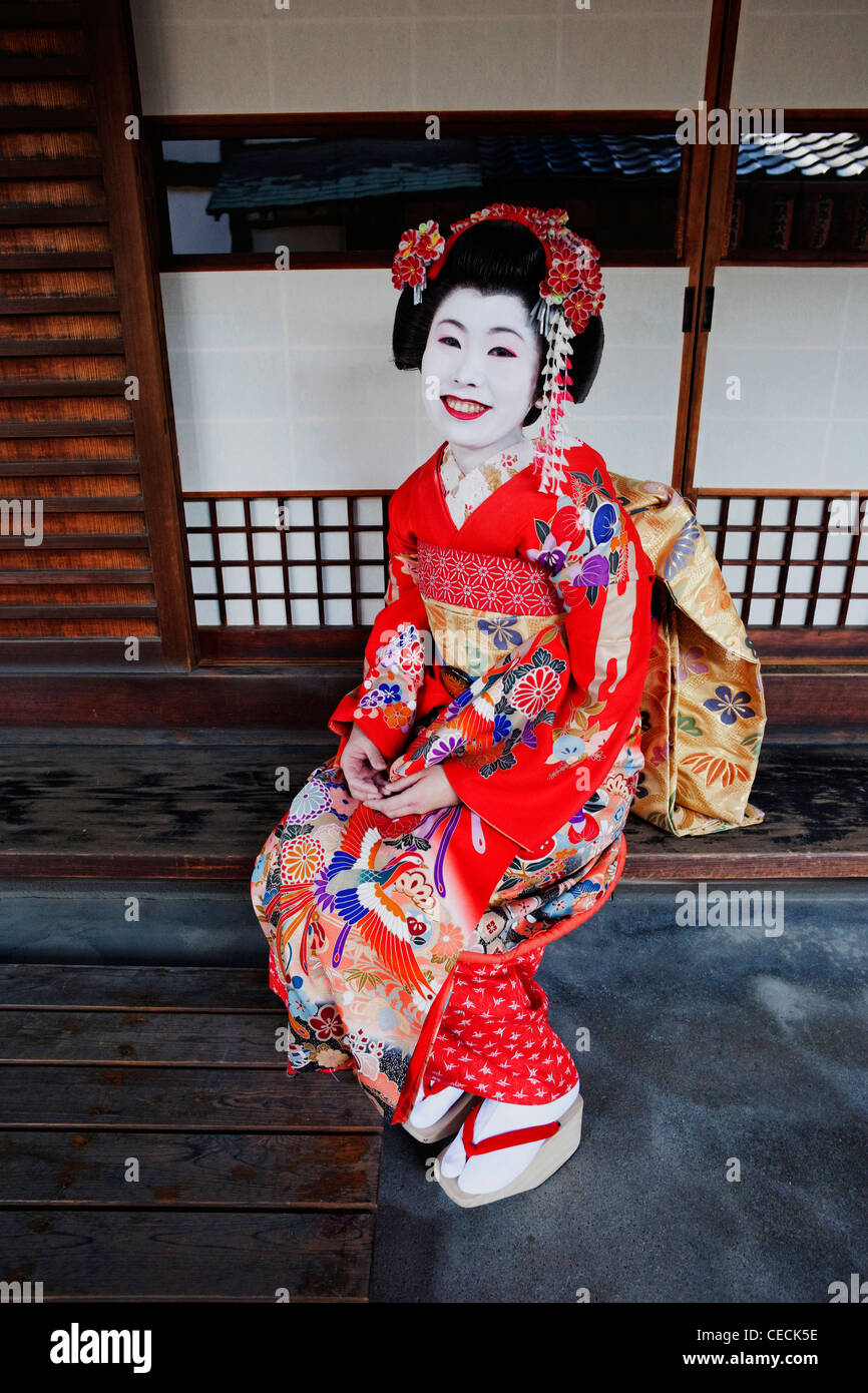 Geisha in red Kimono sitting in front of house Stock Photo - Alamy