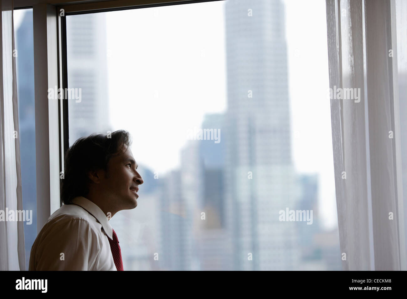 man standing by window looking up at buildings Stock Photo - Alamy