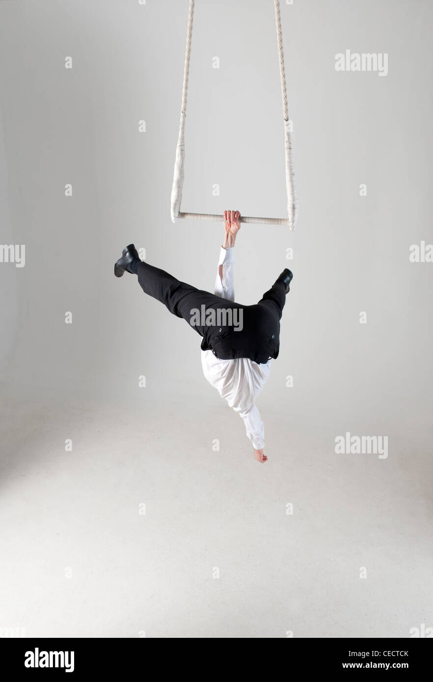 photograph of businessman hanging from trapeze swing Stock Photo - Alamy