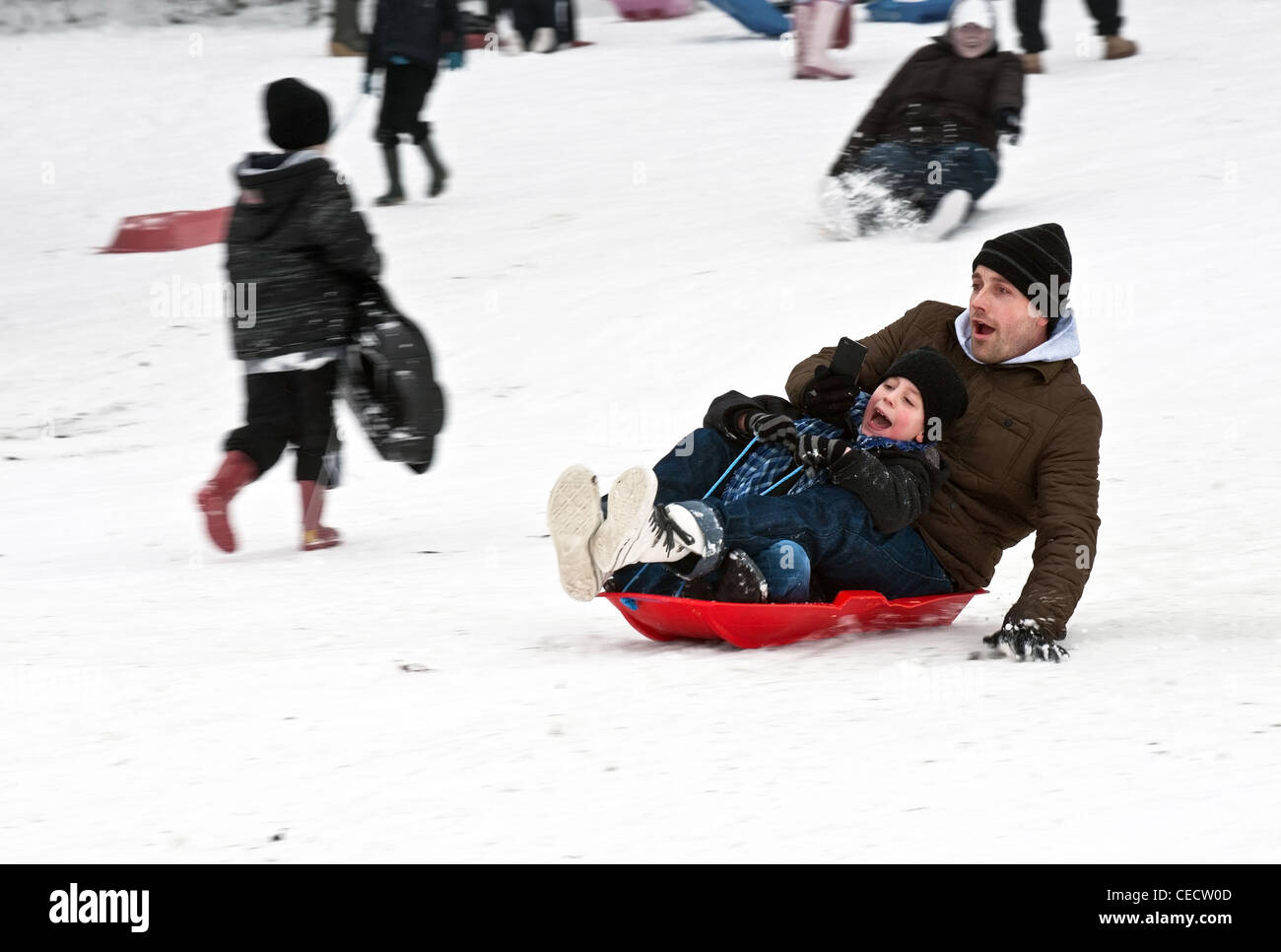 People sledding in the snow Stock Photo - Alamy