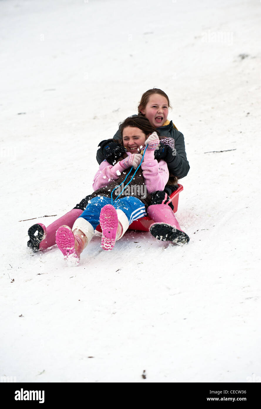 Two girls sledding in the snow Stock Photo - Alamy