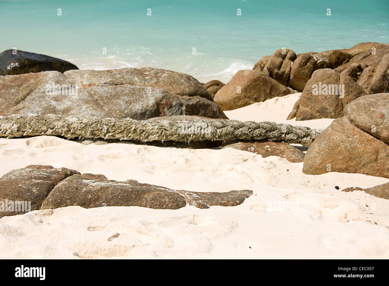 Rope laying on the beach in between rocks Stock Photo - Alamy