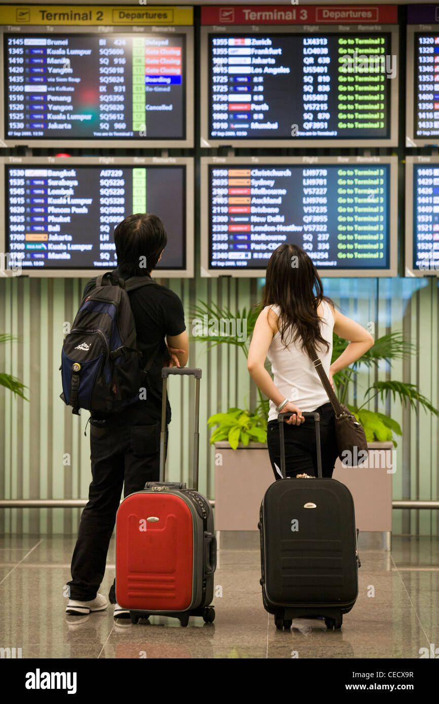 Passengers look at flight departure and arrival information on ...