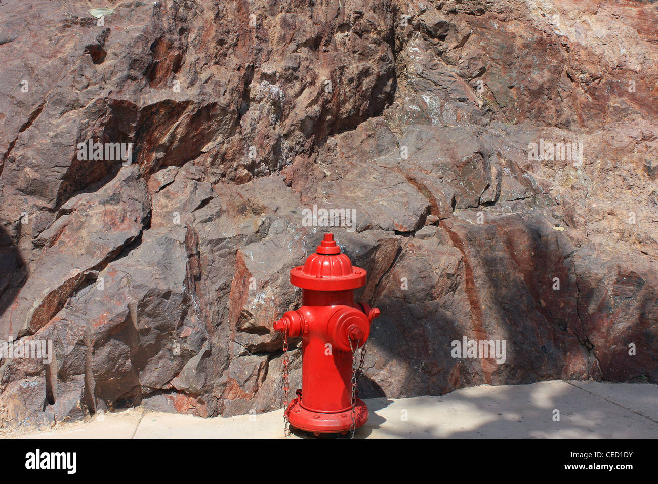 A red fire hydrant at roadside with rocks in background Stock Photo - Alamy
