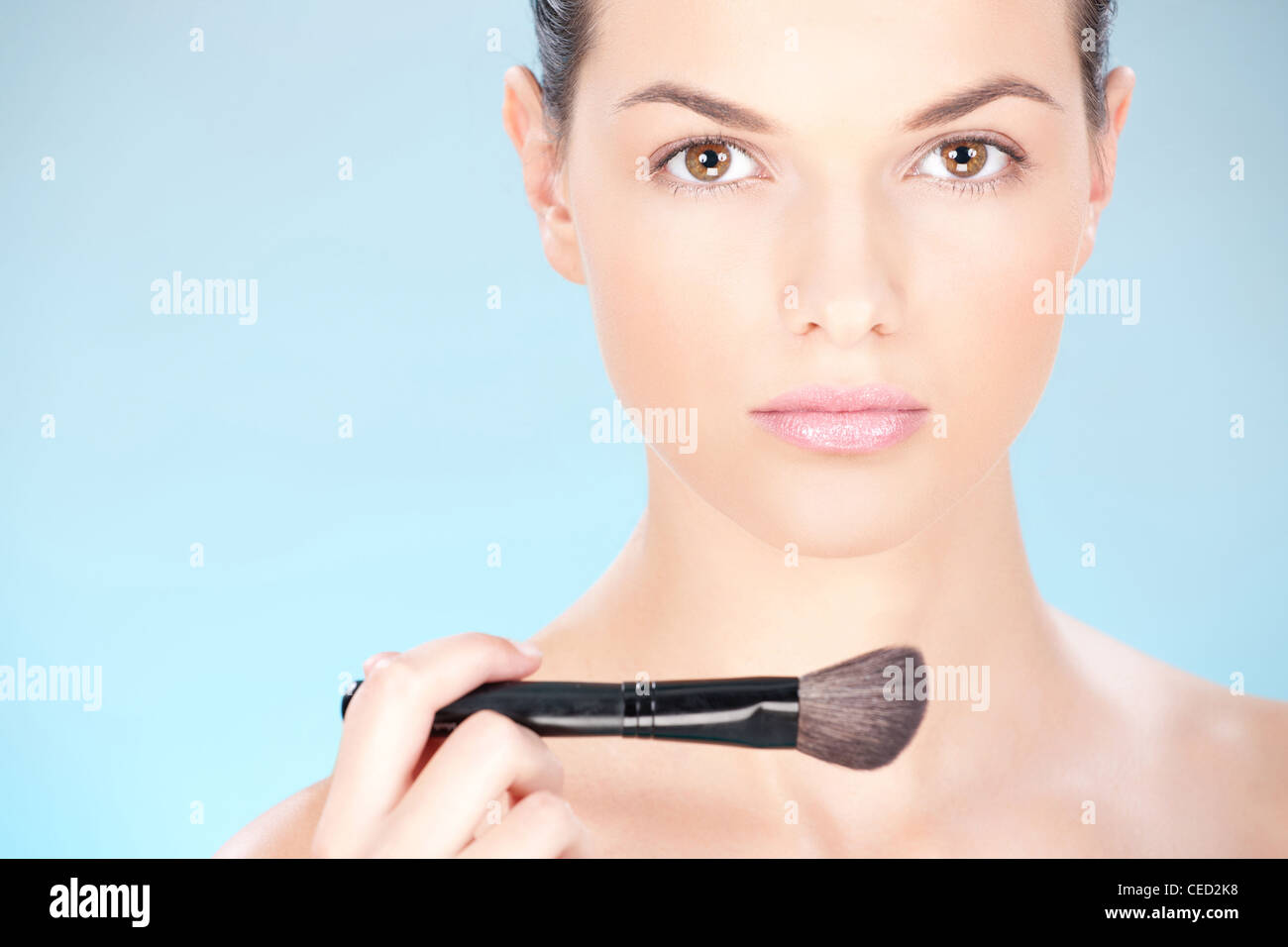 Portrait of a pretty young woman holding powder brush Stock Photo - Alamy