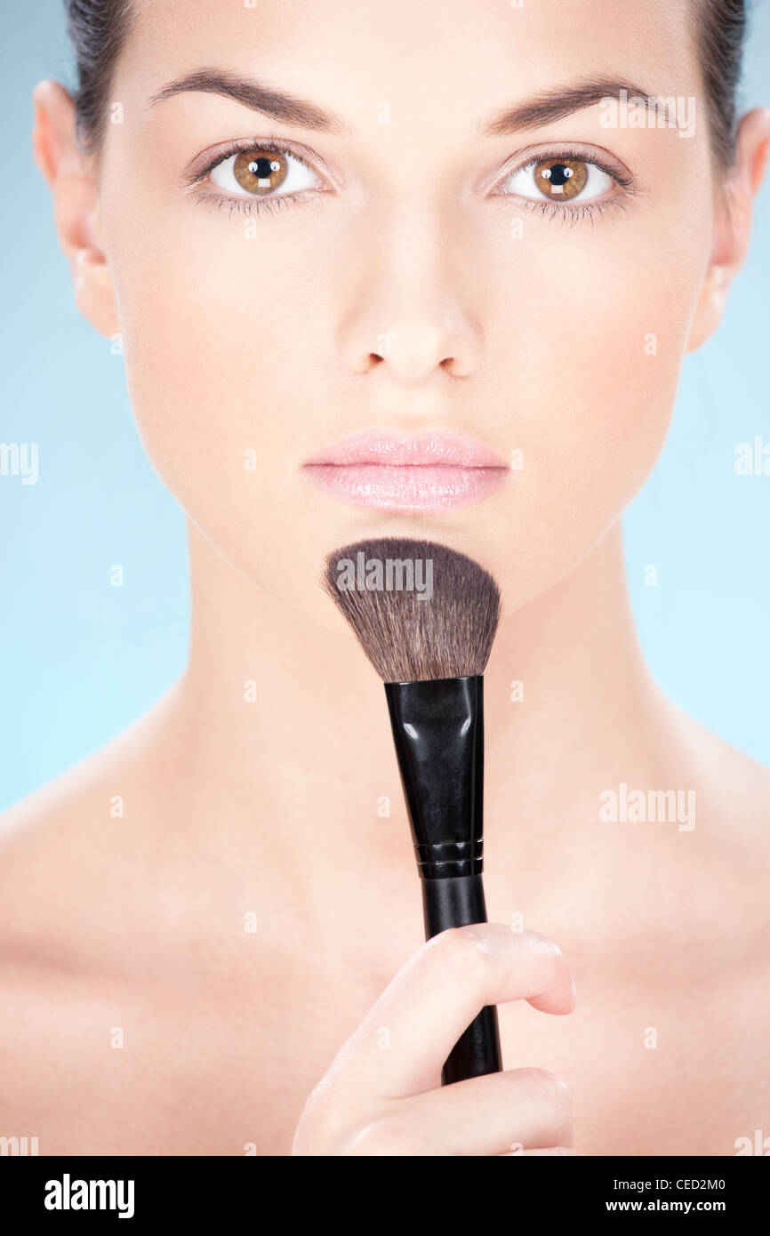 Portrait of a pretty young woman holding powder brush Stock Photo - Alamy