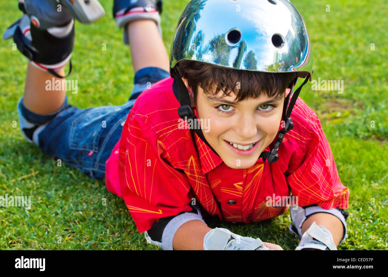happy boy in roller blades gear laying on grass Stock Photo - Alamy