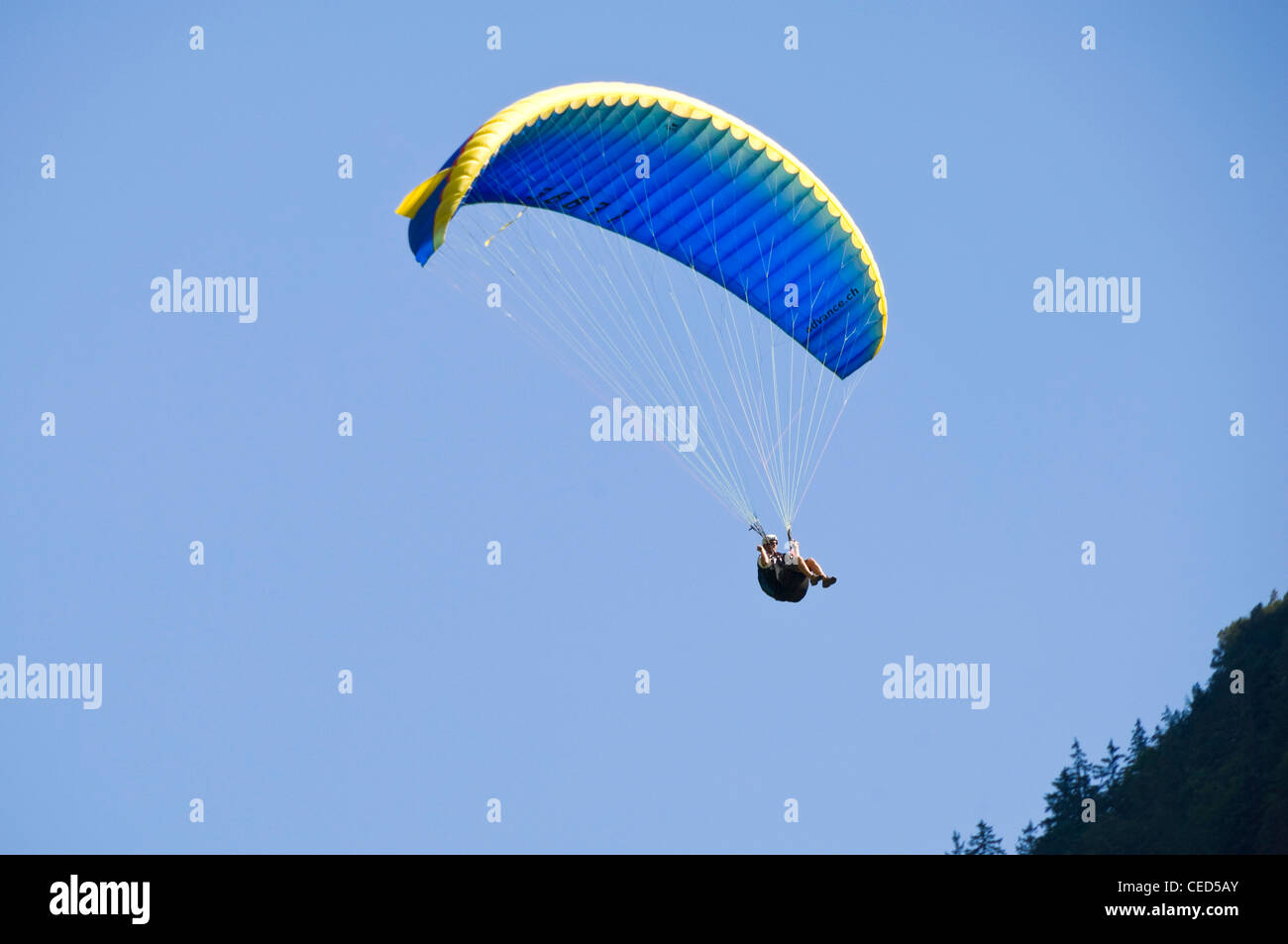 Horizontal view of a paraglider with a bright blue canopy in the sky ...