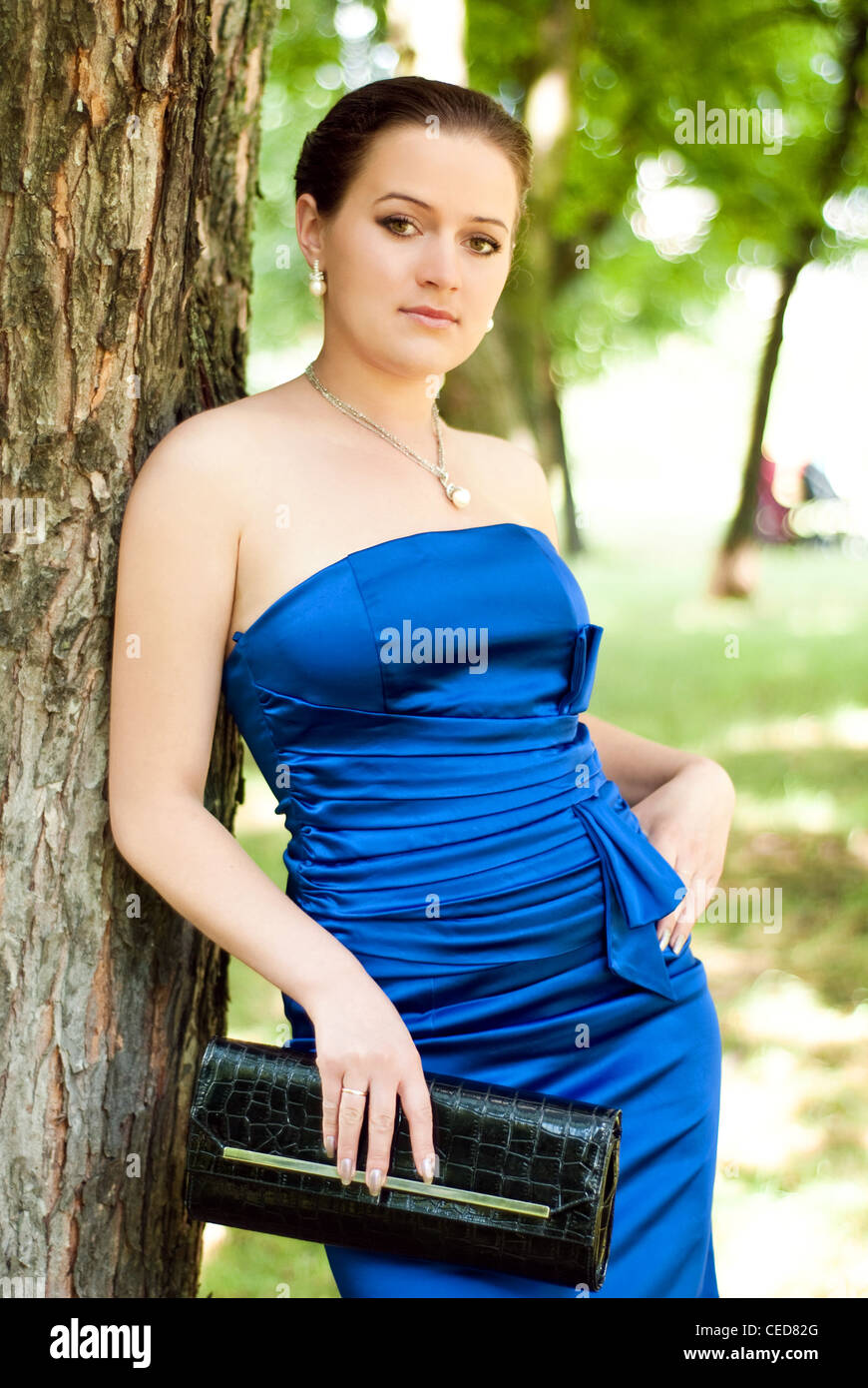 Portrait of gorgeous model with purse in park Stock Photo - Alamy