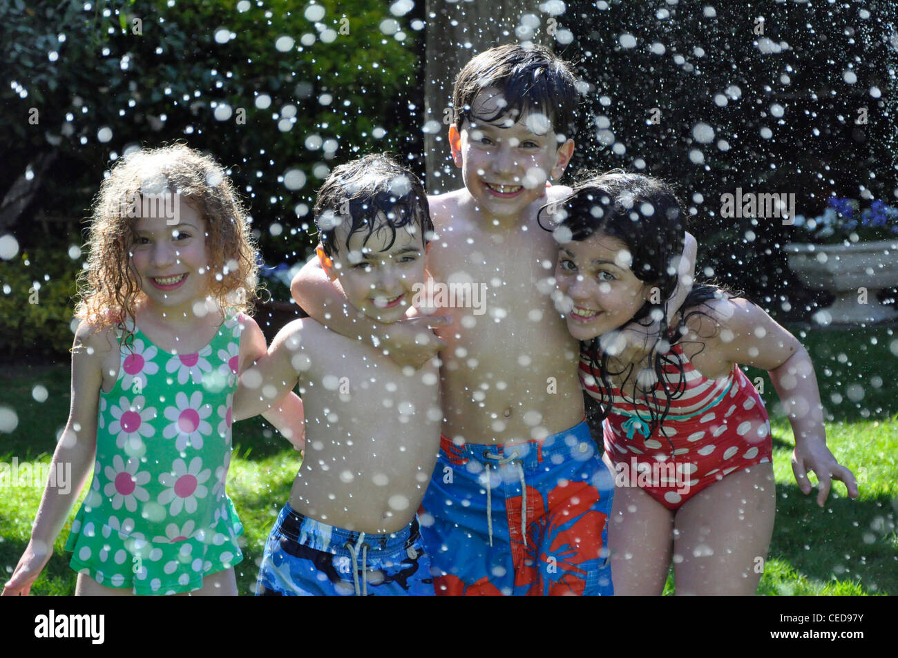 Kids with water spray summer fun Stock Photo - Alamy