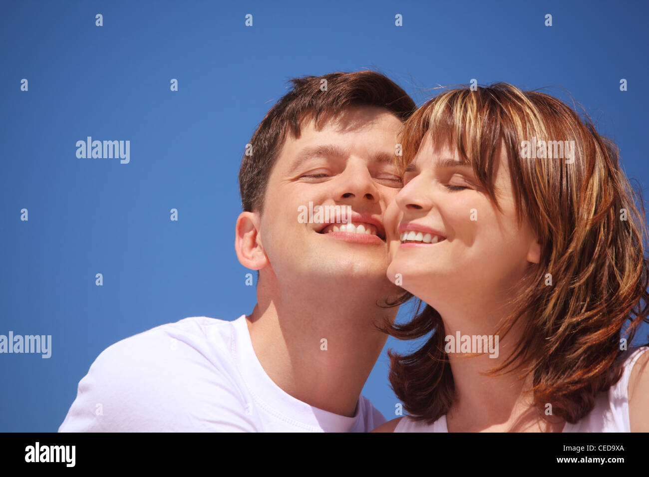 attractive pair against blue sky, touching by cheeks Stock Photo - Alamy