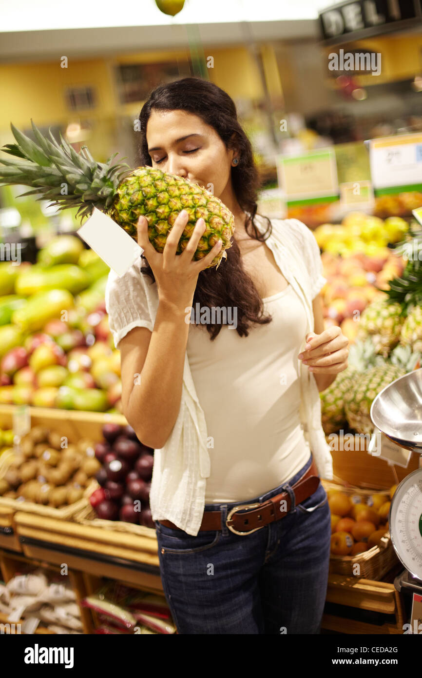 Hispanic woman smelling pineapple in grocery store Stock Photo - Alamy