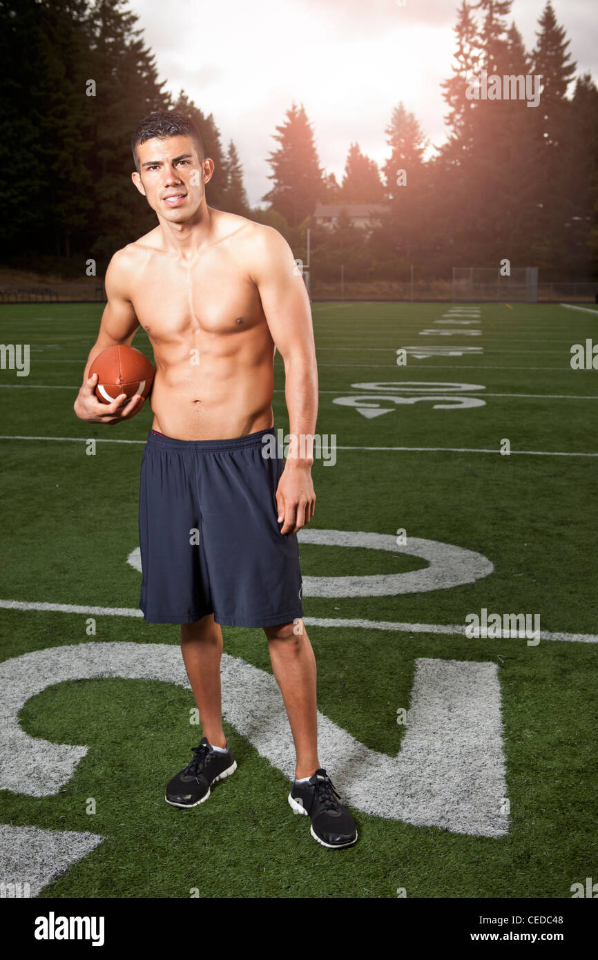 Hispanic athlete holding football Stock Photo - Alamy