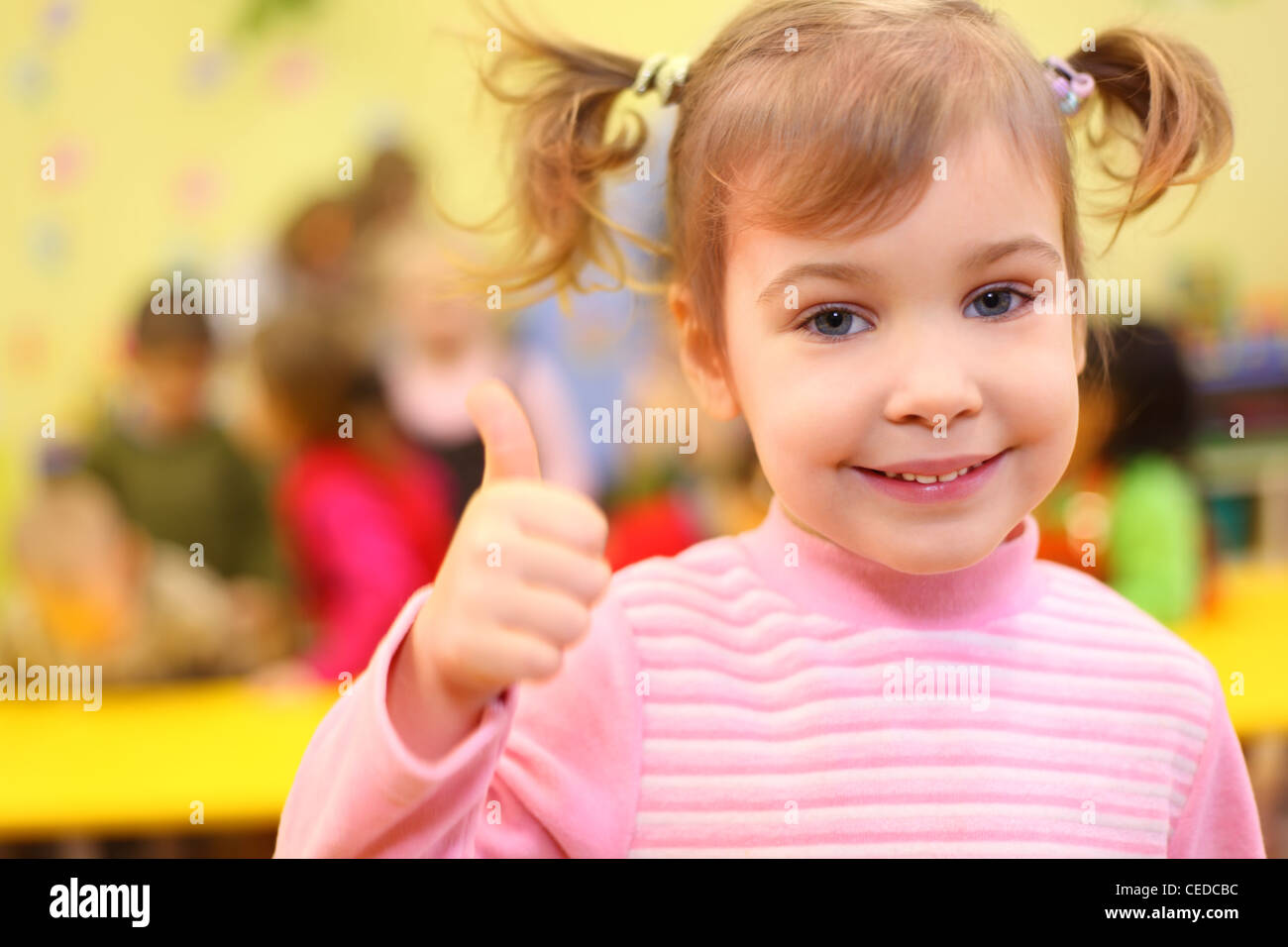 Little smiling girl in kindergarten shows sign ok Stock Photo - Alamy