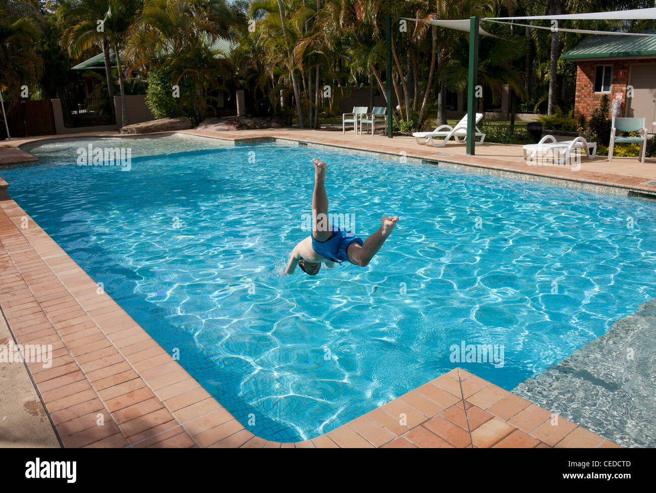 teenage boy jumping into a swimming pool in summer Stock Photo - Alamy