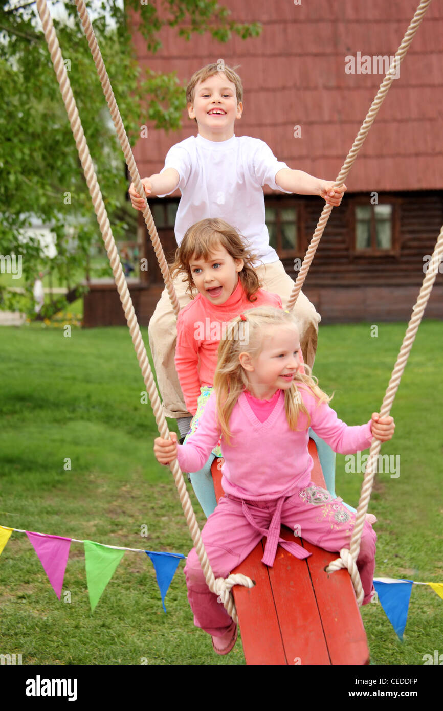 Three children on swing Stock Photo - Alamy