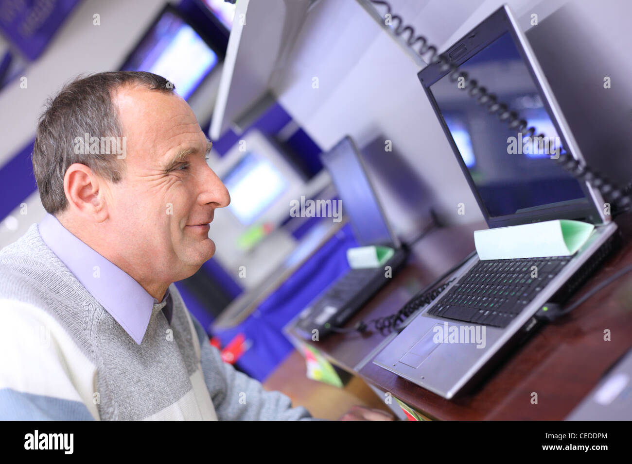elderly man in shop looks at laptop Stock Photo - Alamy
