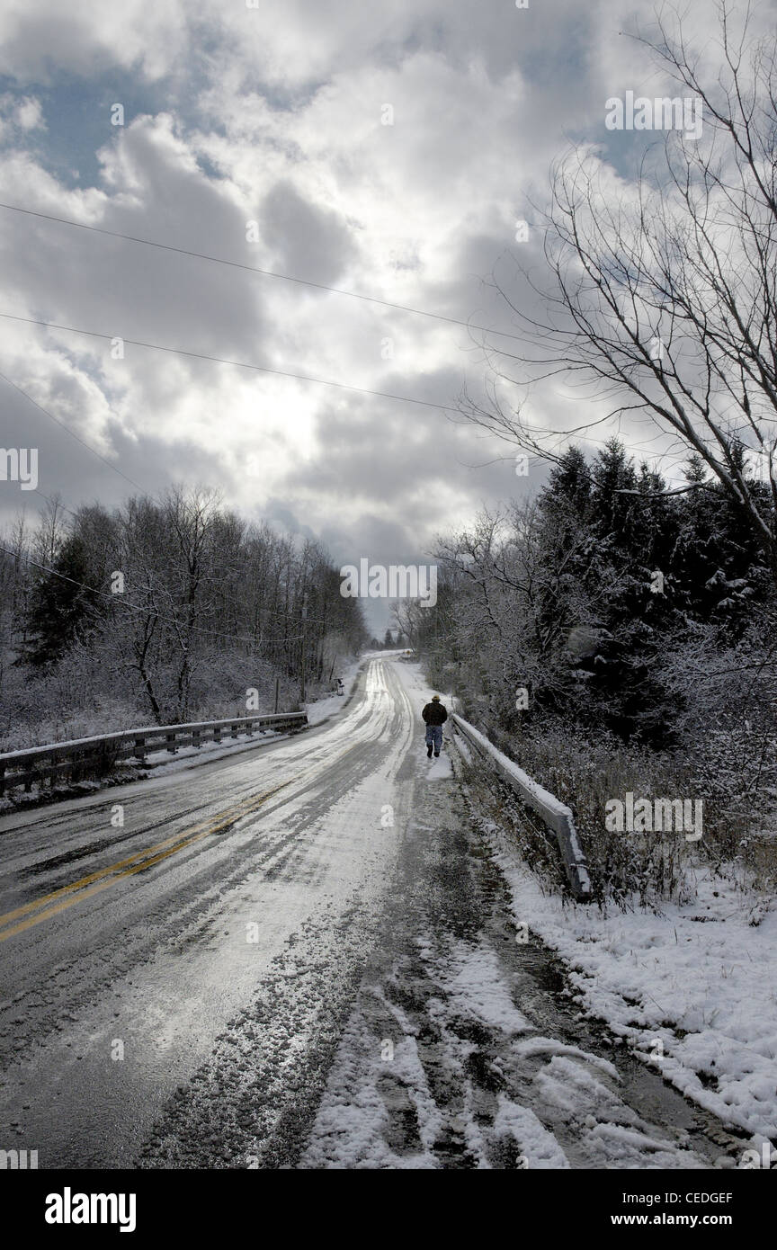 a man walking alone on a road with snow in winter Stock Photo - Alamy