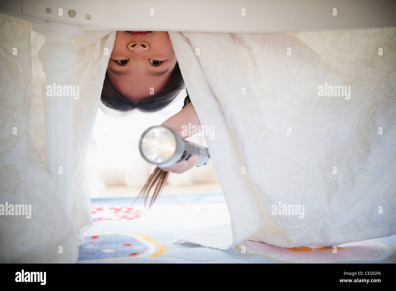 Korean girl looking under bed with flashlight Stock Photo - Alamy