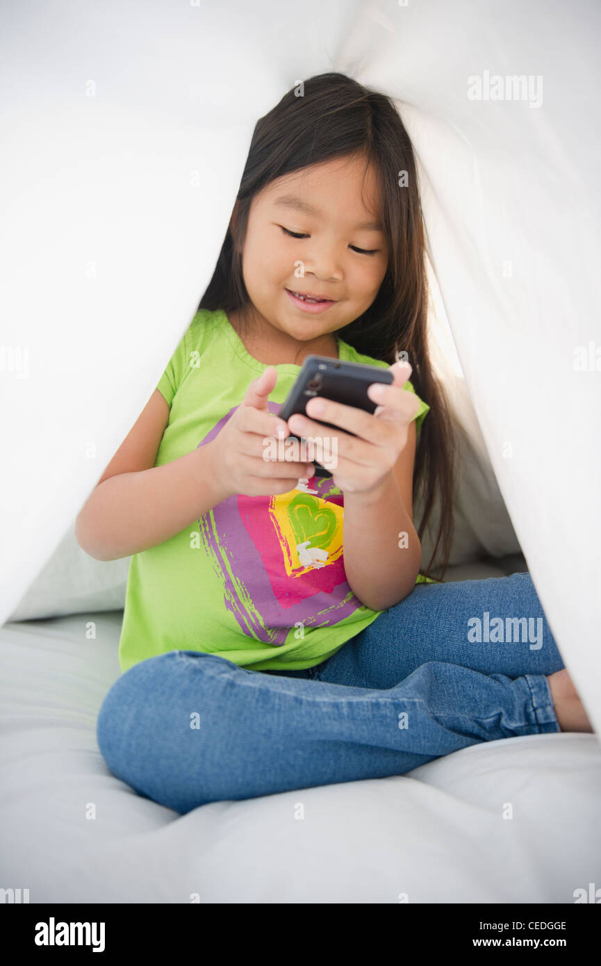 Korean girl using cell phone under sheet Stock Photo - Alamy