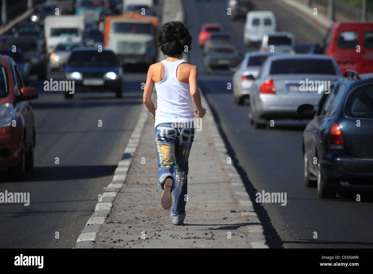 behind girl runs on highway middle in city Stock Photo - Alamy