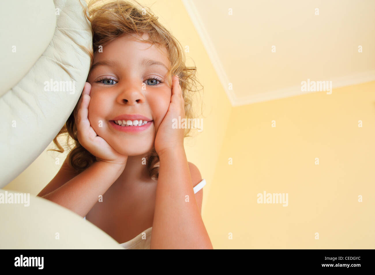 pretty smiling little girl in cosy room, foreshortening from below ...