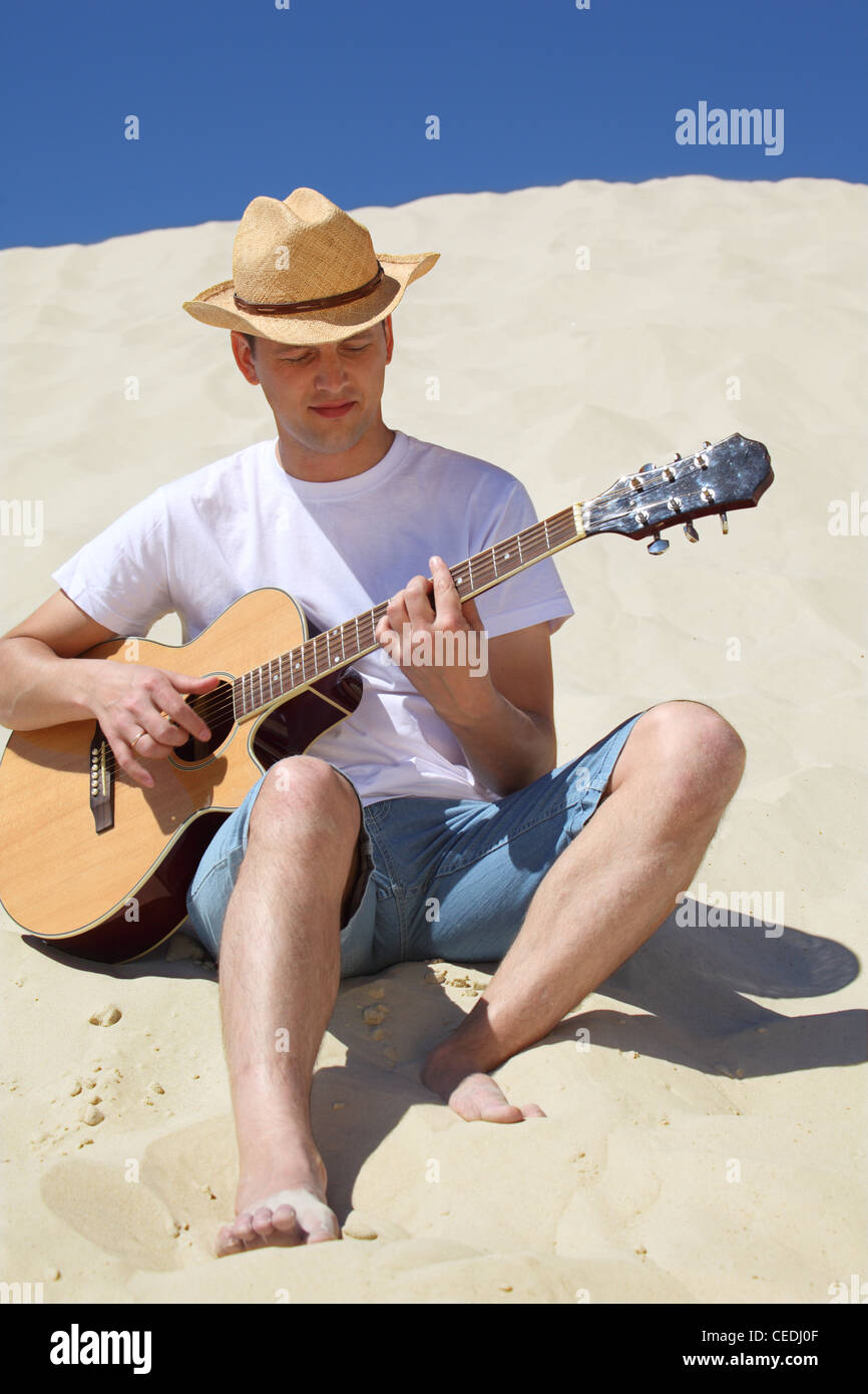 guy in straw hat plays guitar sitting on sand Stock Photo - Alamy