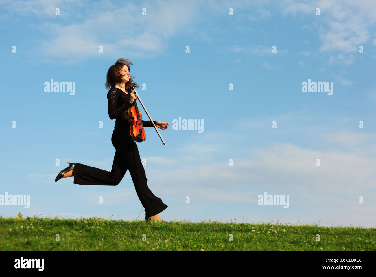 girl with violin runs on grass against sky, side view Stock Photo - Alamy