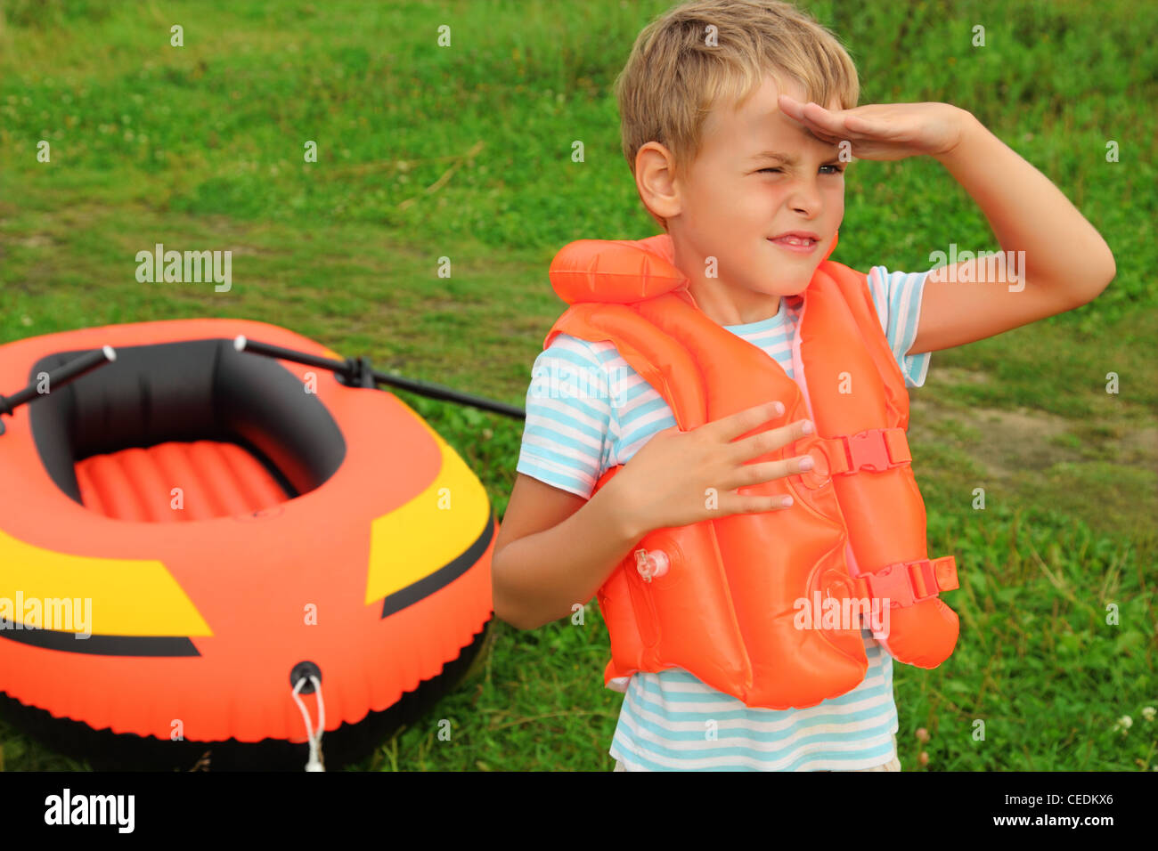 boy keeps watch and inflatable boat on lawn Stock Photo - Alamy