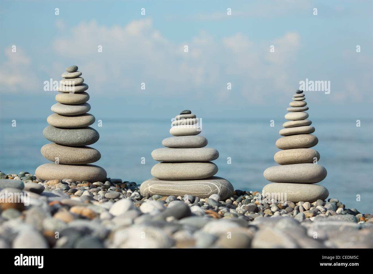 three stone stacks on pebble beach, sunlight Stock Photo - Alamy