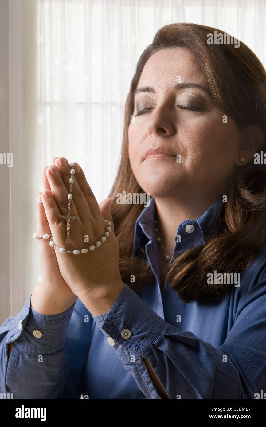 Hispanic woman holding rosary praying Stock Photo - Alamy