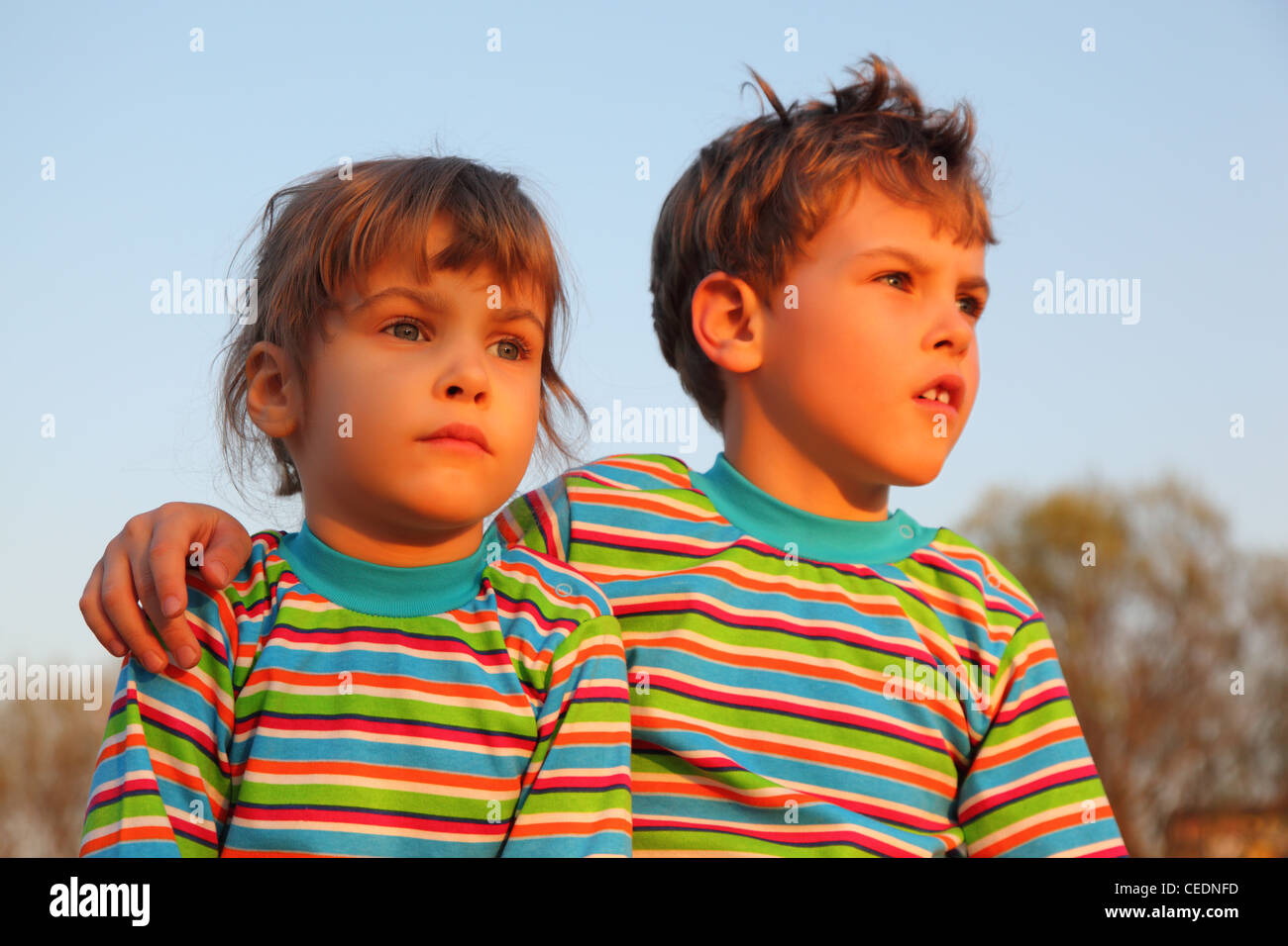 Two children in striped t-shirts, boy embraces girl for a shoulder ...